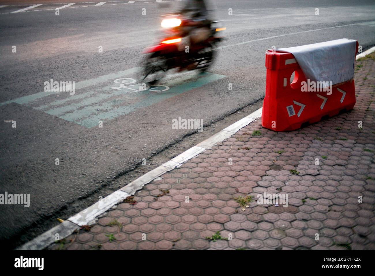 Orange plastic construction barriers on a street with motion motorcycle ...
