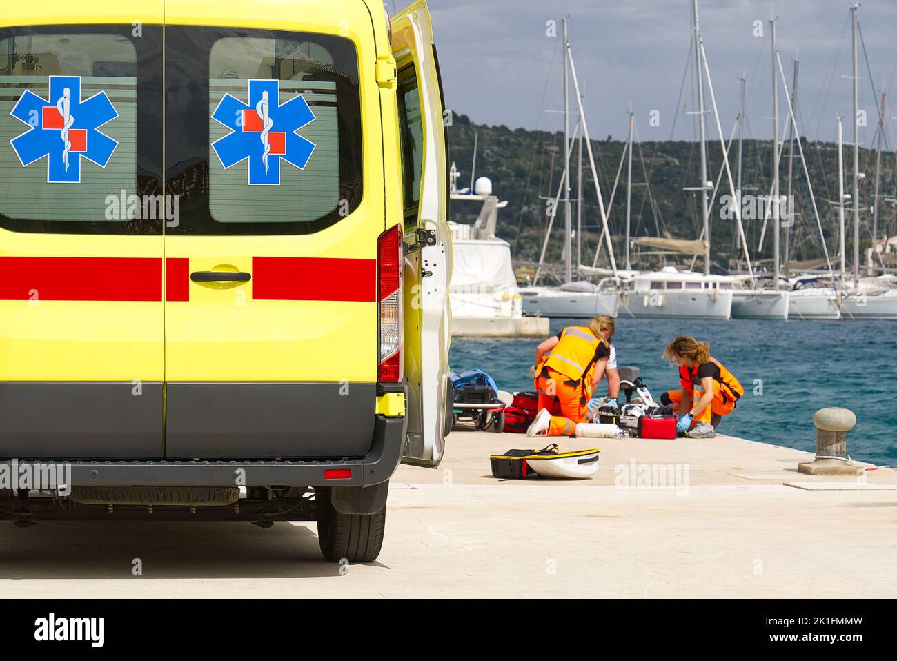 ambulance workers provide first aid to a person in a yacht port. heat ...