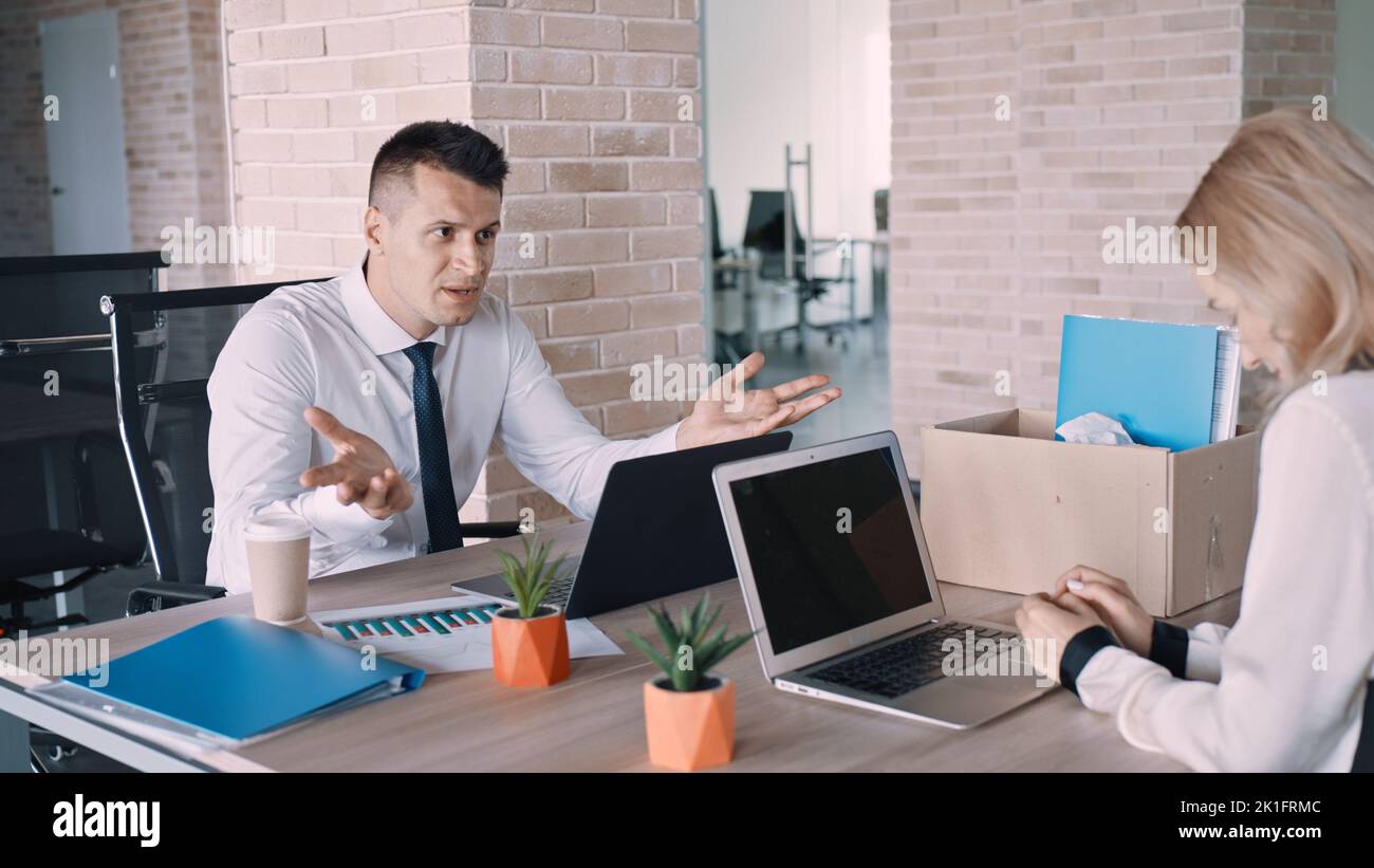 CO-workers in an office, one of them looks angry while the other feels ...