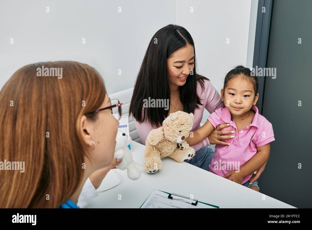 Physician communicates with Asian little girl patient during her visit ...
