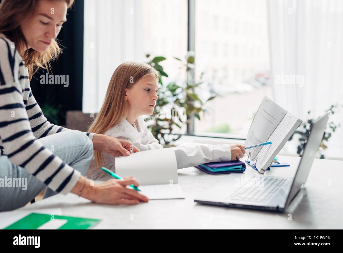 Girl is doing her homework and her mother is checking Stock Photo - Alamy