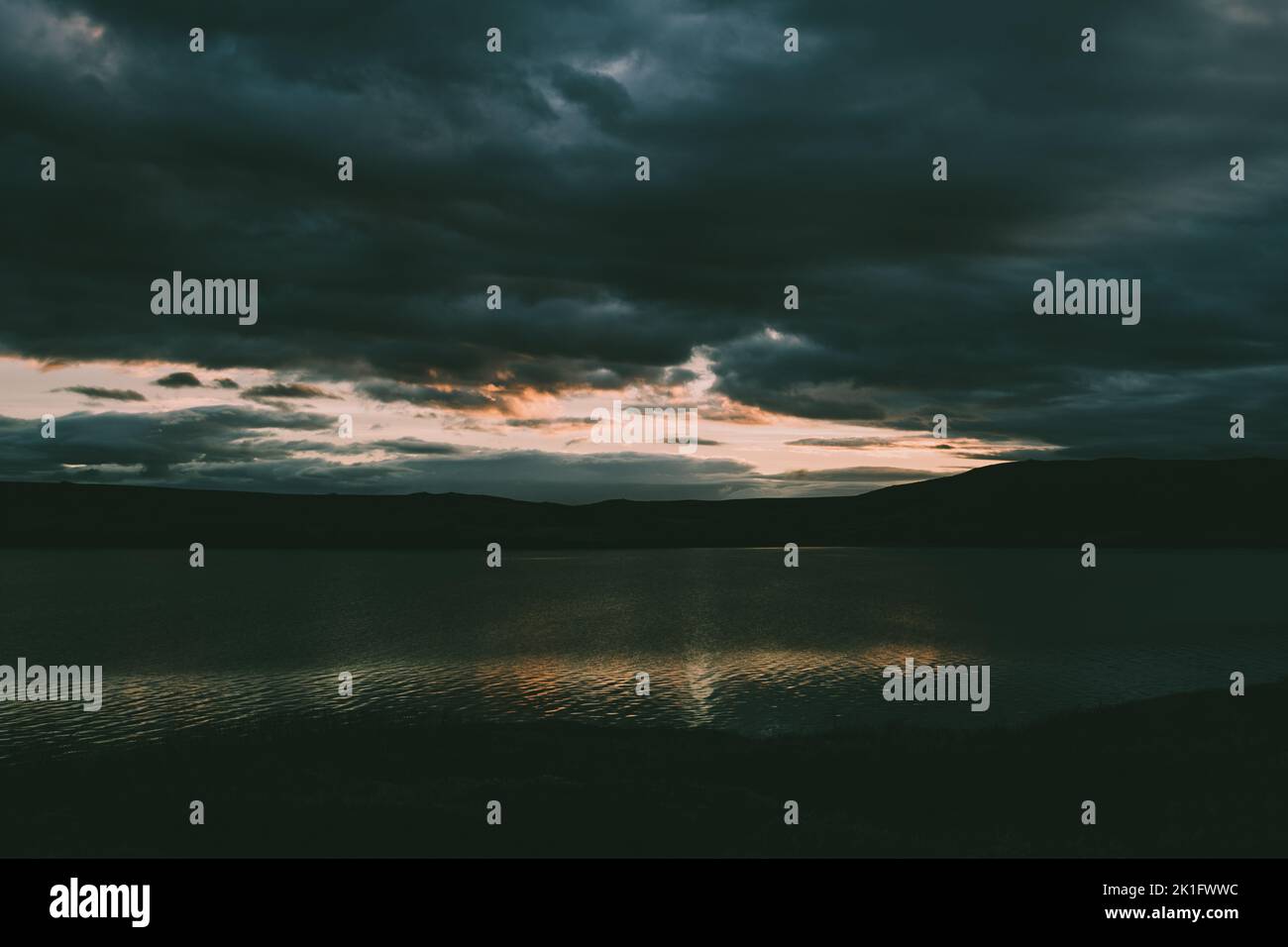Dramatic dark sky with deep blue clouds and pale yellow sun rays above ...