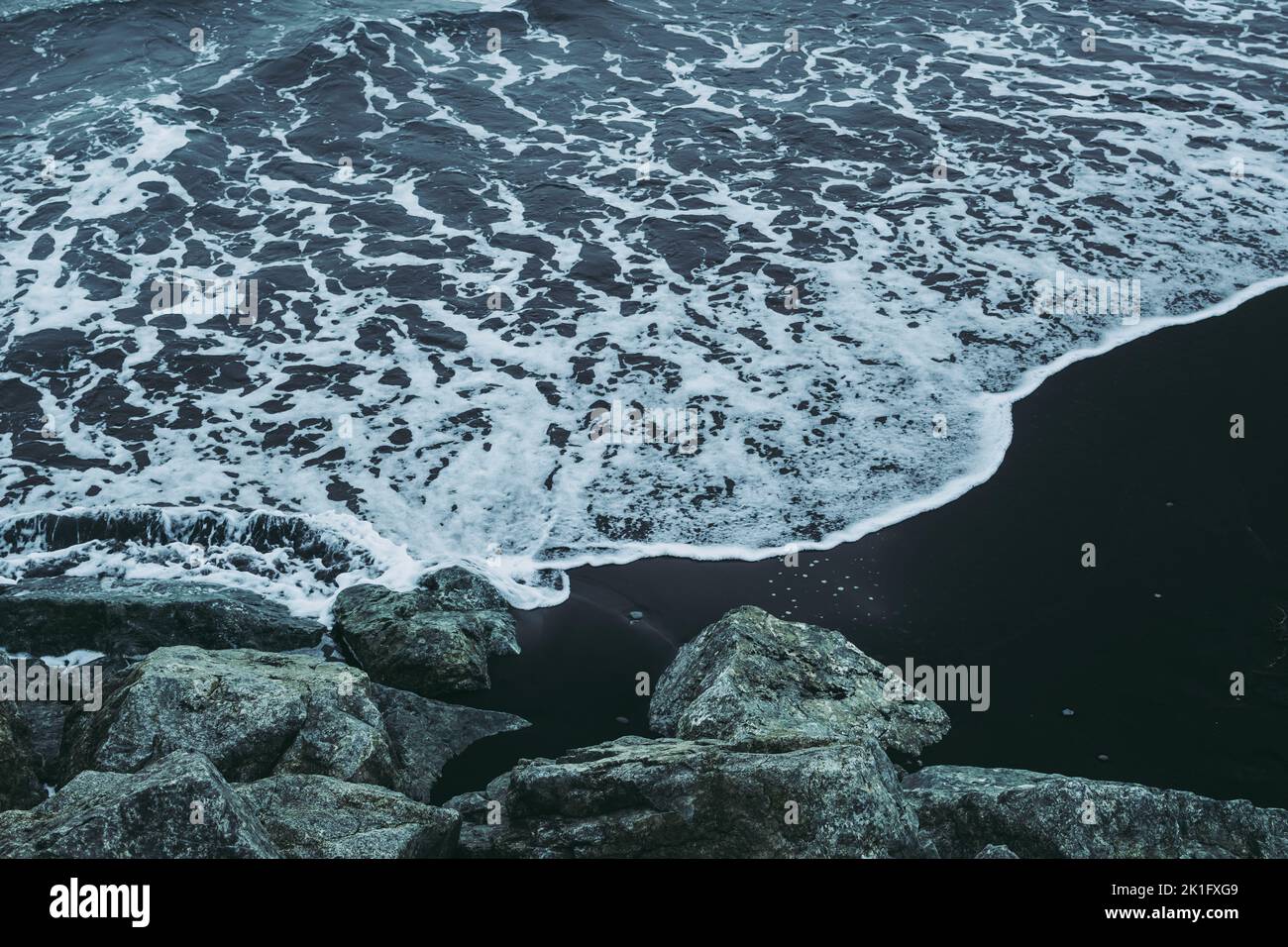 Cold waters of Atlantic Ocean on black sand beach in Iceland. View from ...
