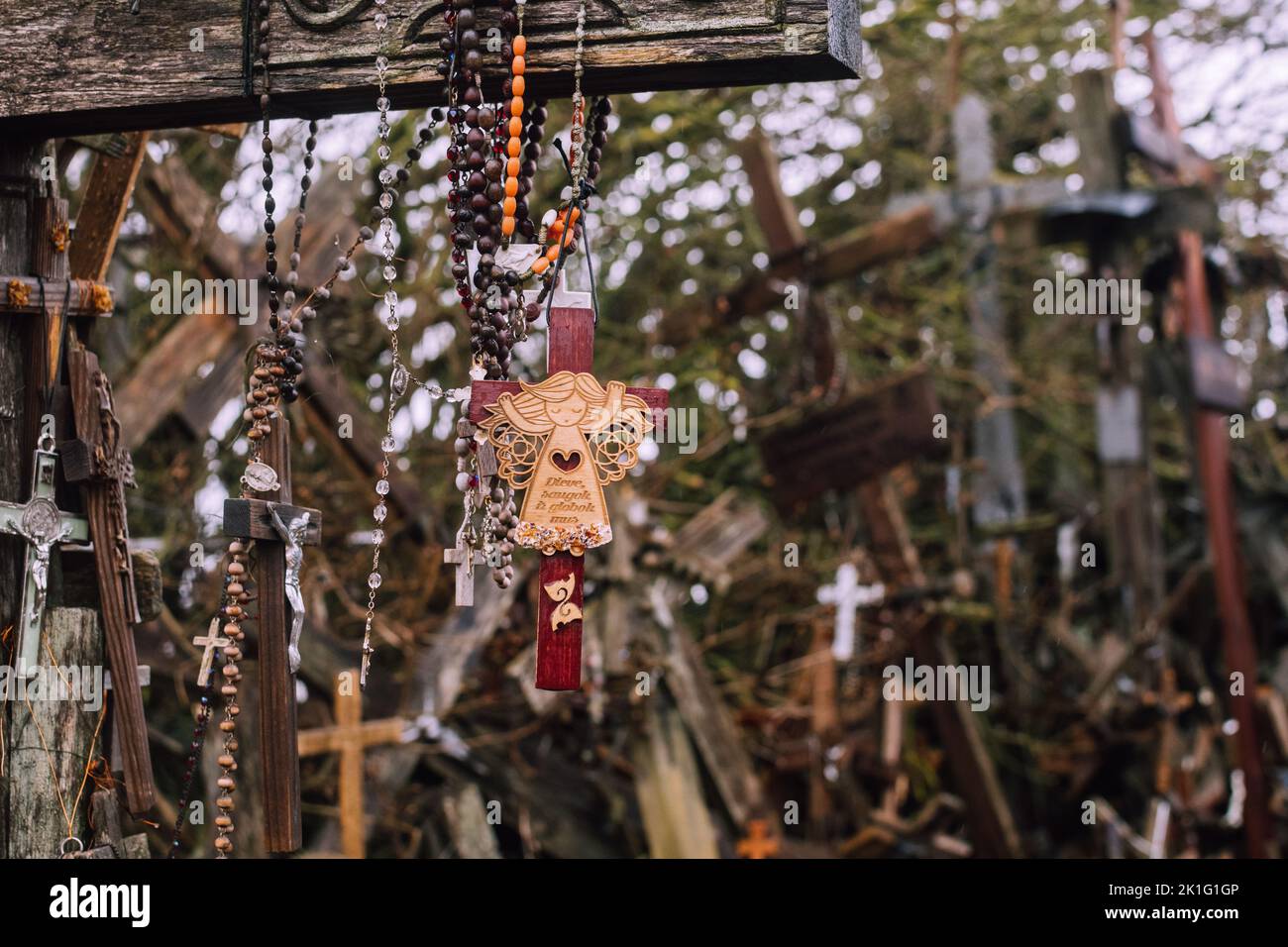 Figure of an angel hanging on the wooden cross against green background ...