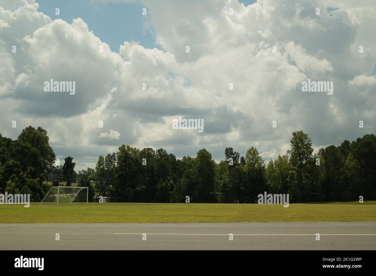 A country landscape with a road, football field, and green trees under ...