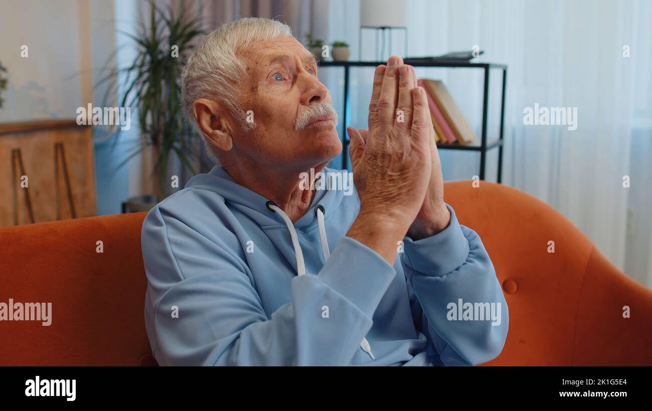Please, God help. Man praying sincerely with folded arms, looking ...