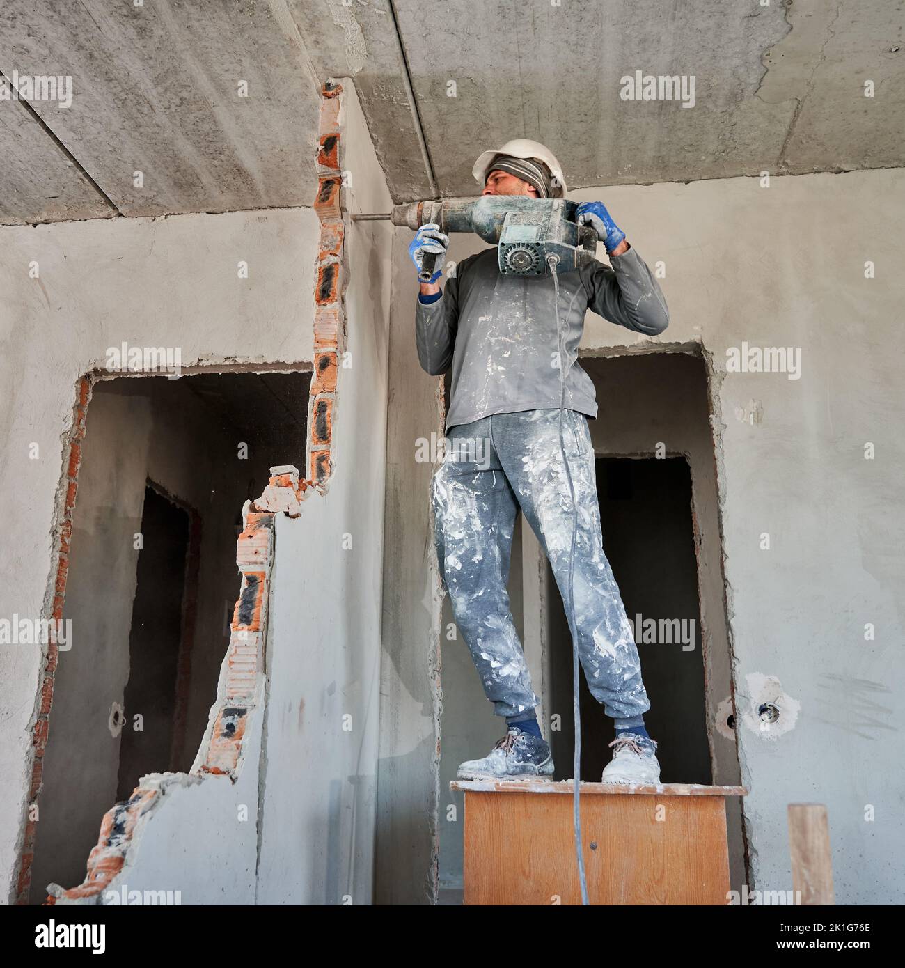 Full length of man in workwear drilling wall with hammer drill. Male ...