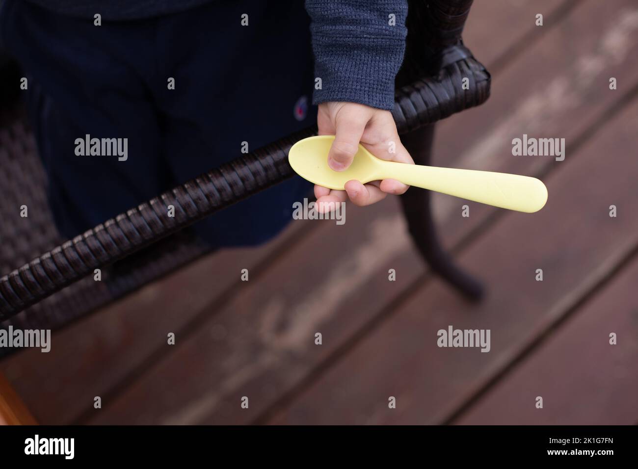 Hand of kid holding handy yellow spoon for children nutrition top view ...