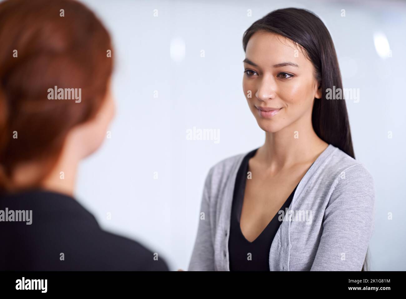 Office connections. A cropped shot of two young professionals talking ...
