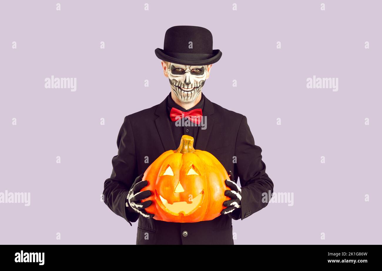 Cheerful man with spooky Halloween makeup holding glowing pumpkin on ...