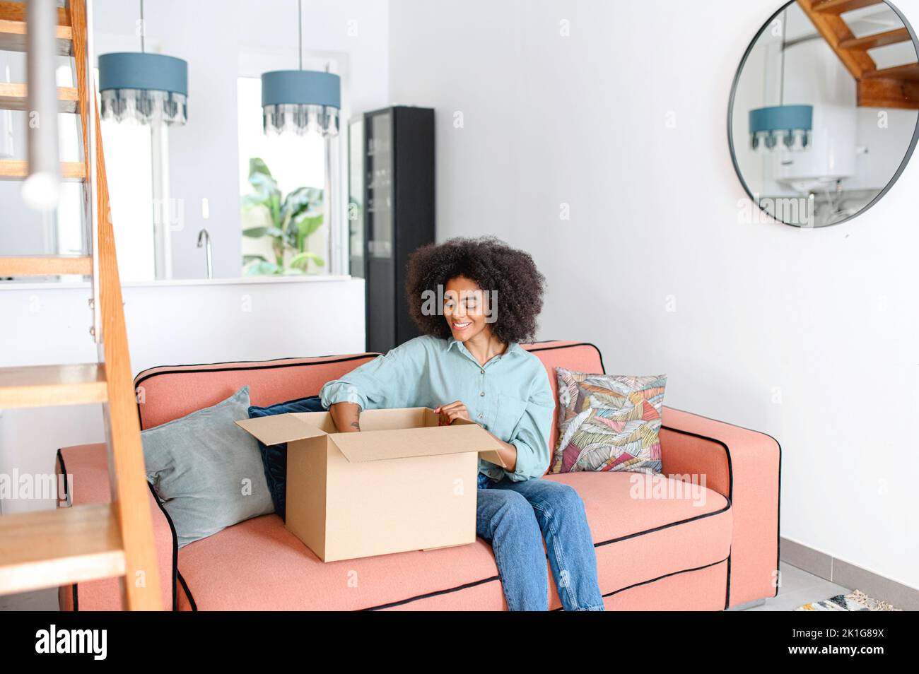 Happy multiracial woman is looking at her new parcels, sitting on the ...
