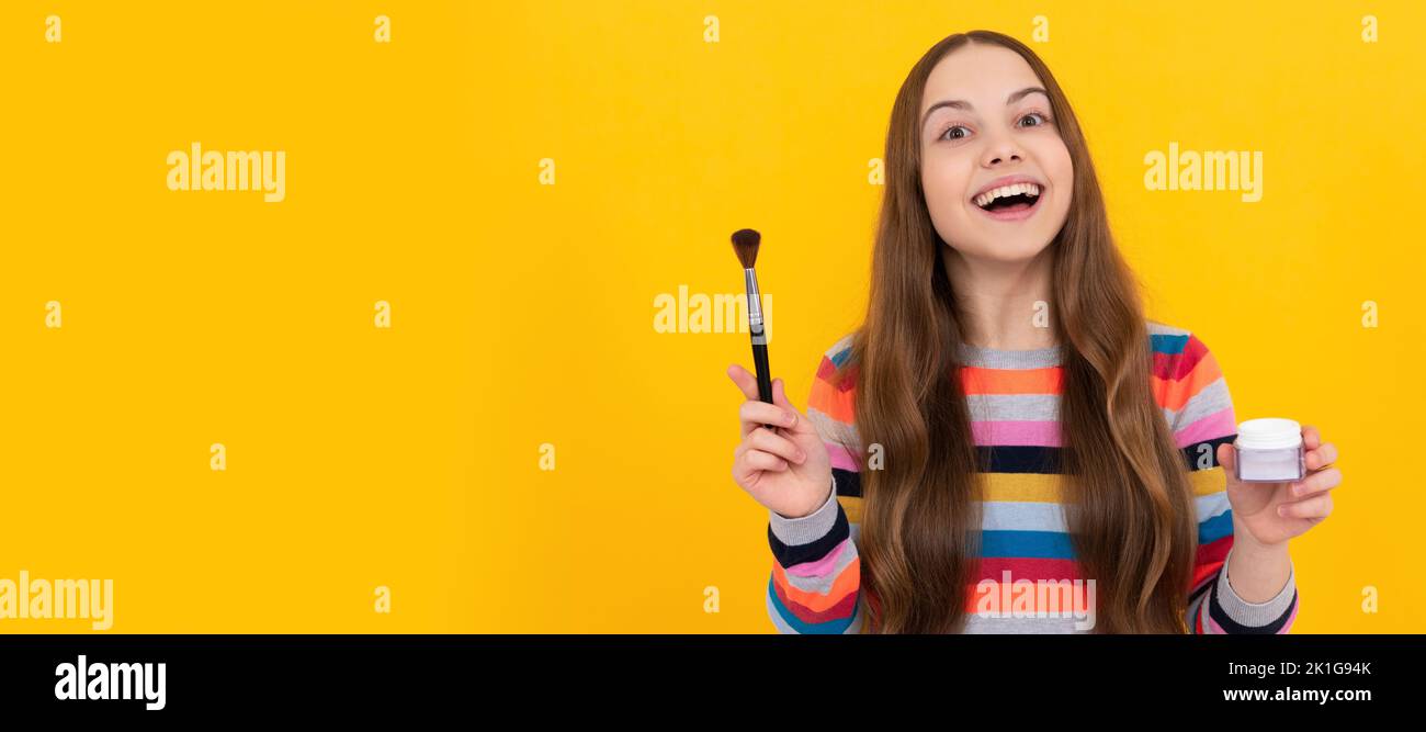 Happy kid apply cosmetics with foundation brush yellow background ...