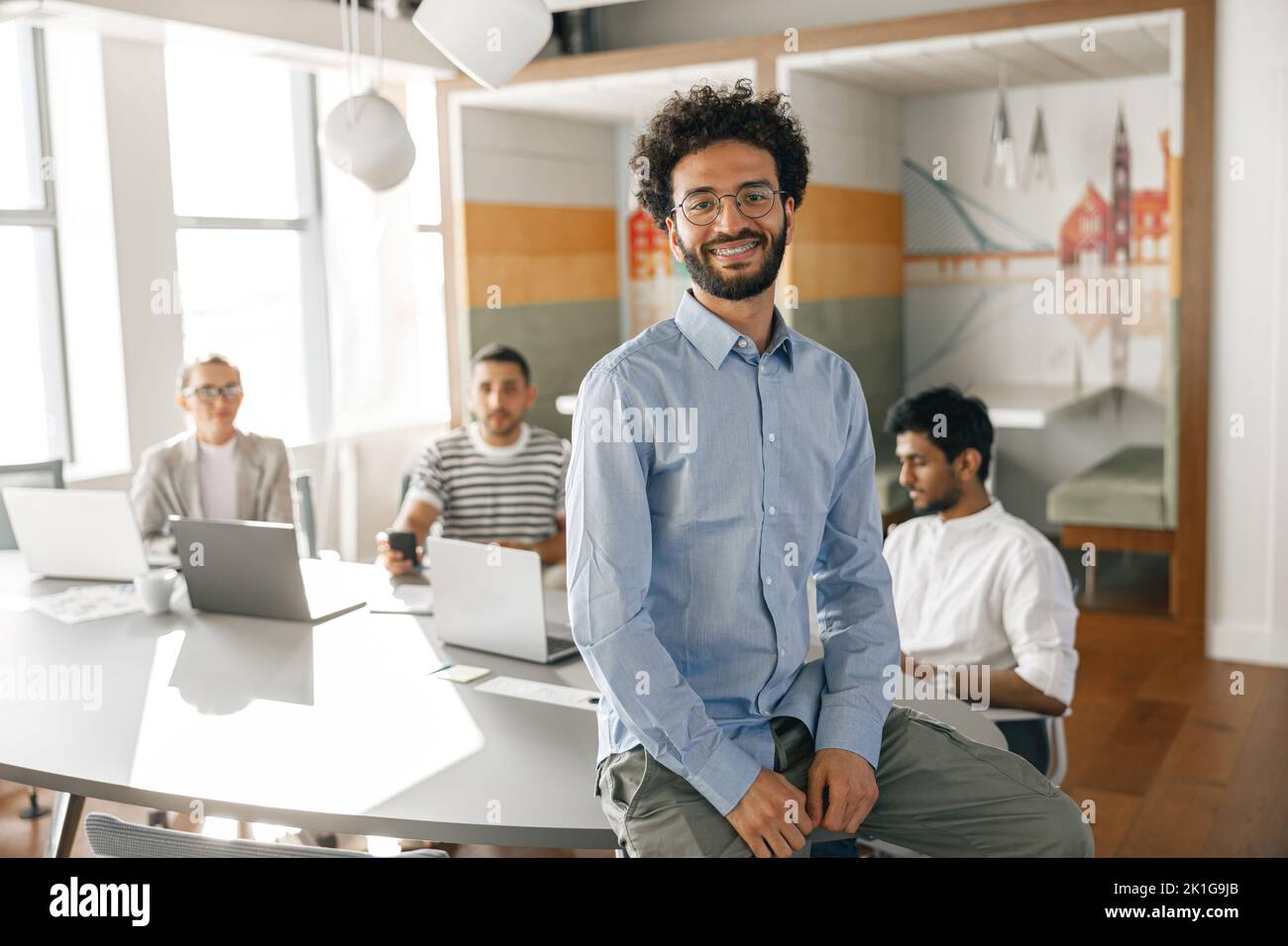Portrait of smiling businessman standing in modern office on colleagues ...