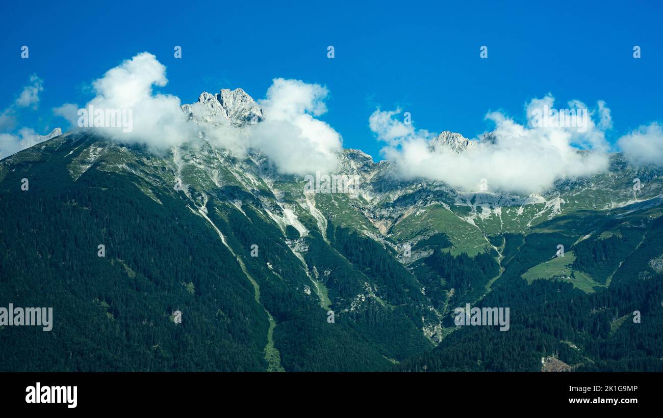A shot of a mountain range covered with green grass on a sunny and ...