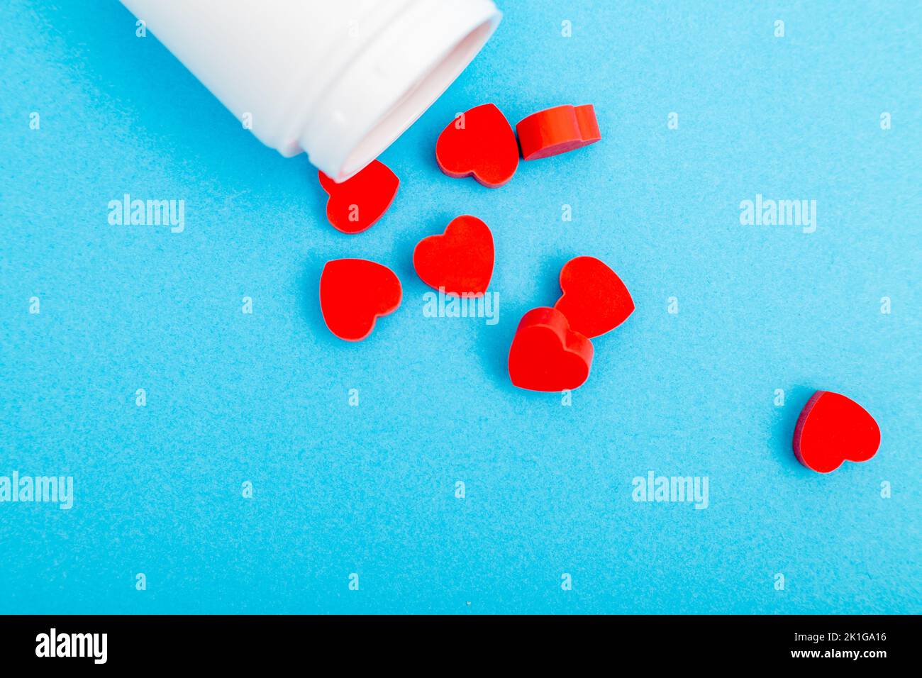 Red heart shaped pills with plastic bottle on blue background.Concept ...