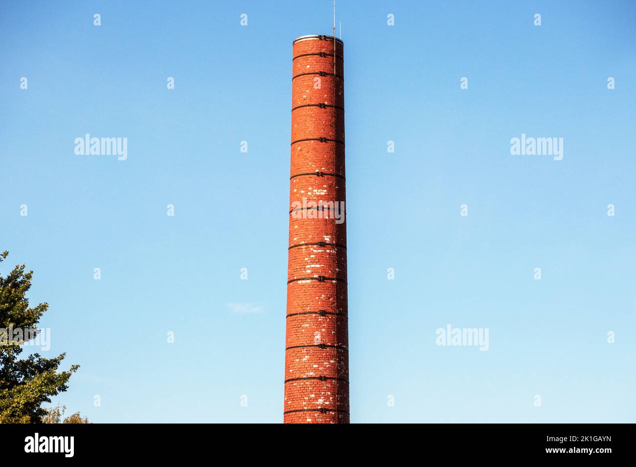 A very tall and dark brown chimney in the middle of the park with green ...