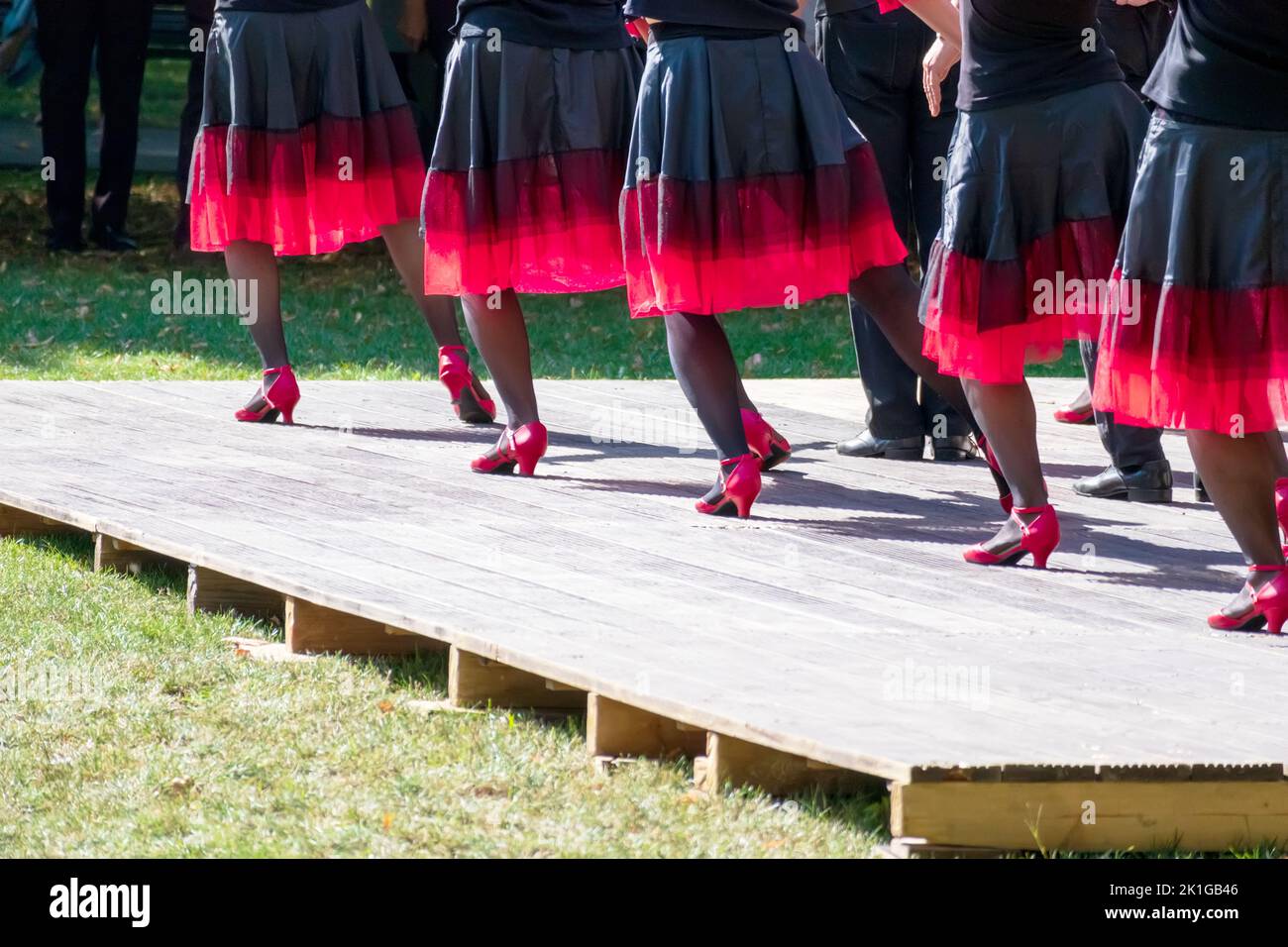 The dance team dances on the light brown stage with pink shoes and ...