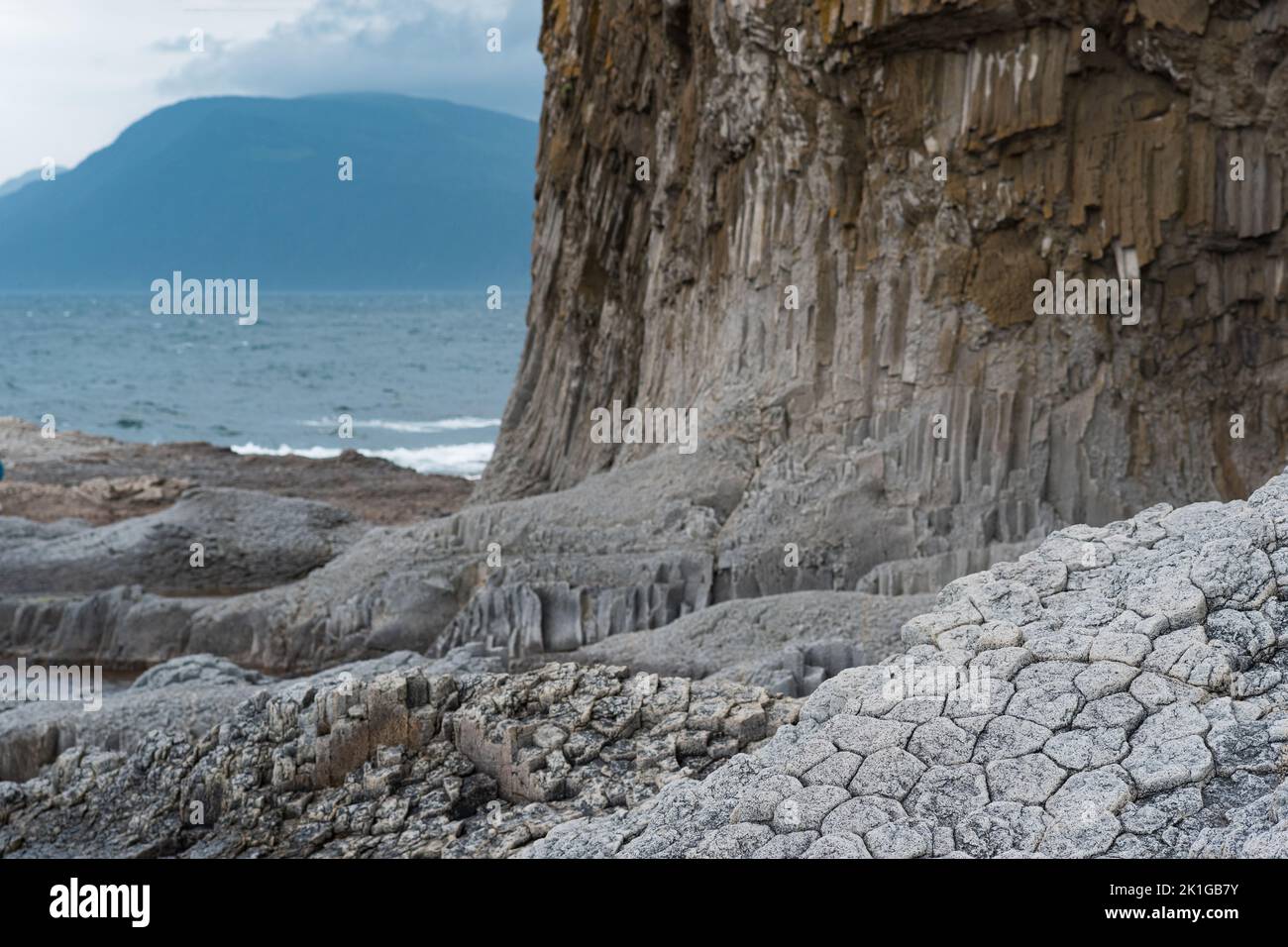 cloudy rocky seashore formed by columnar basalt against the backdrop of ...