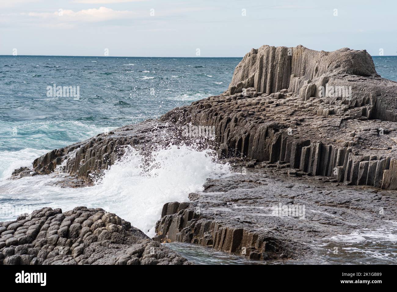 rocks formed by columnar basalt among the sea surf, Cape Stolbchaty on ...