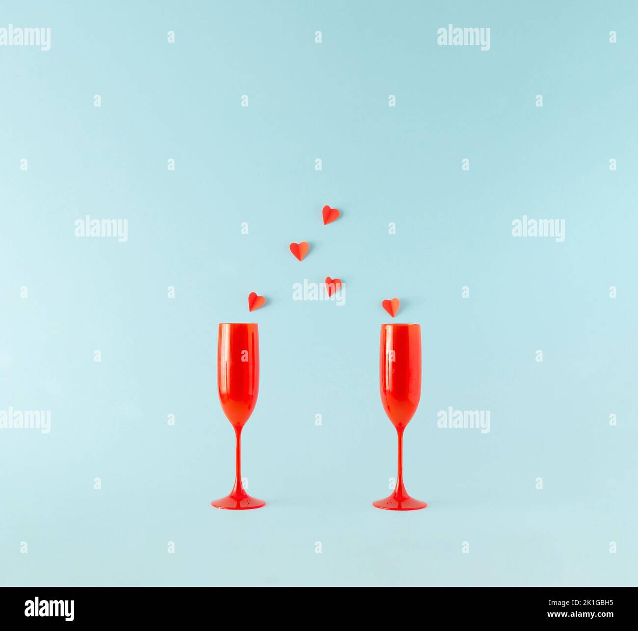 Two red drinking glasses with a red paper hearts flying out of the ...