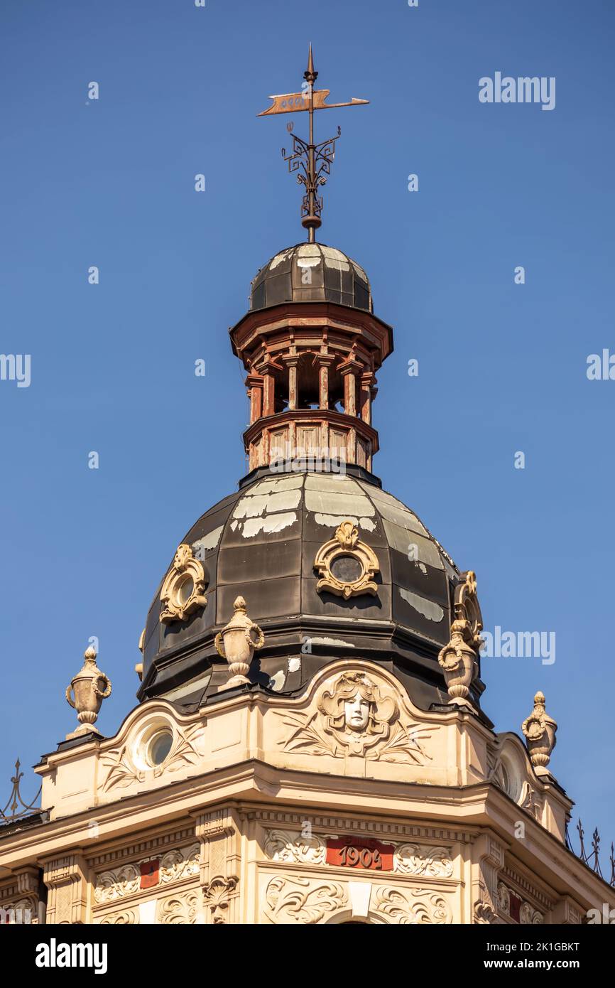 A church with a brown wall and a pointed metal tip in the middle of the ...