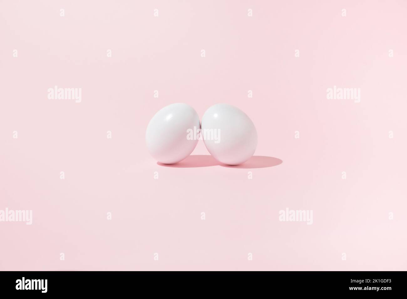 Easter scene with two white eggs leaning against each other on pink ...
