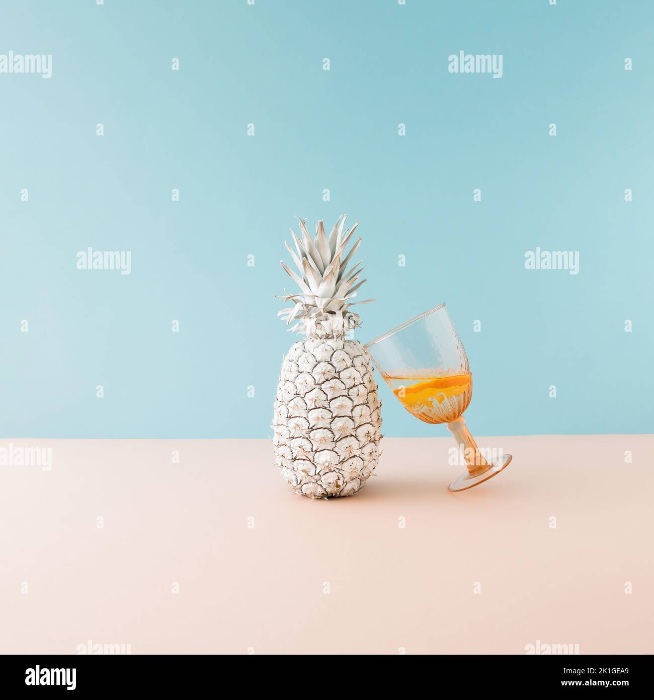 White pineapple and drinking glass with liquor and slice of orange on ...