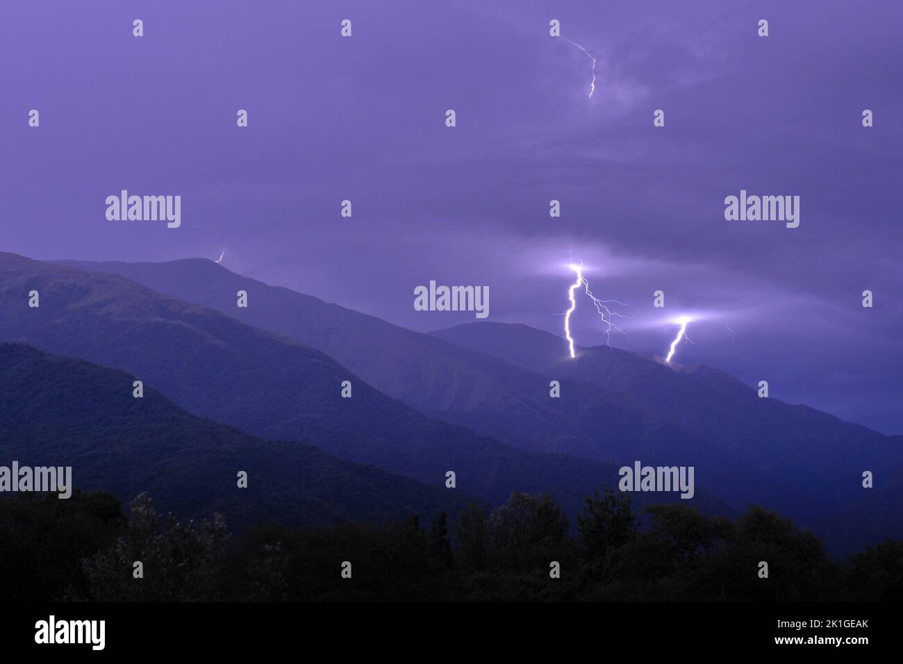 A sudden flash of lightning striking the peak of a mountain under a ...