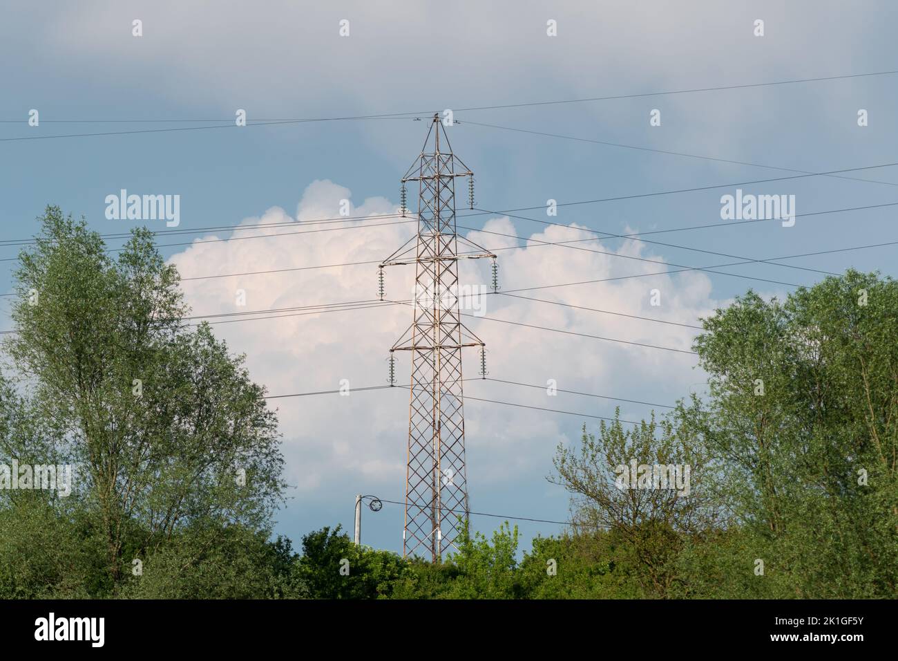 Transmission line pylon close up against big cumulonimbus cloud ...
