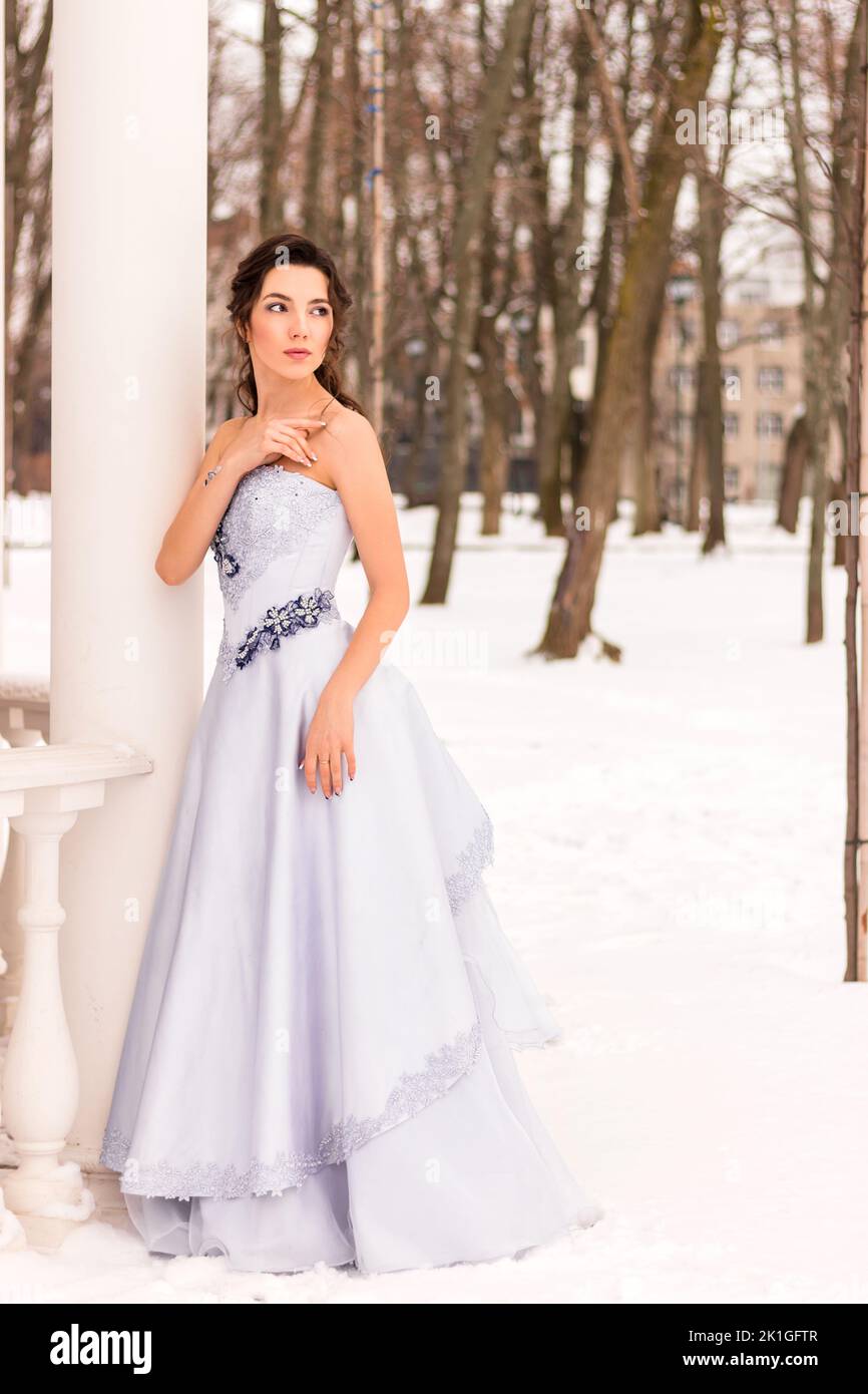 Beautiful woman in a luxurious blue fairy-tale dress in a snowy forest ...