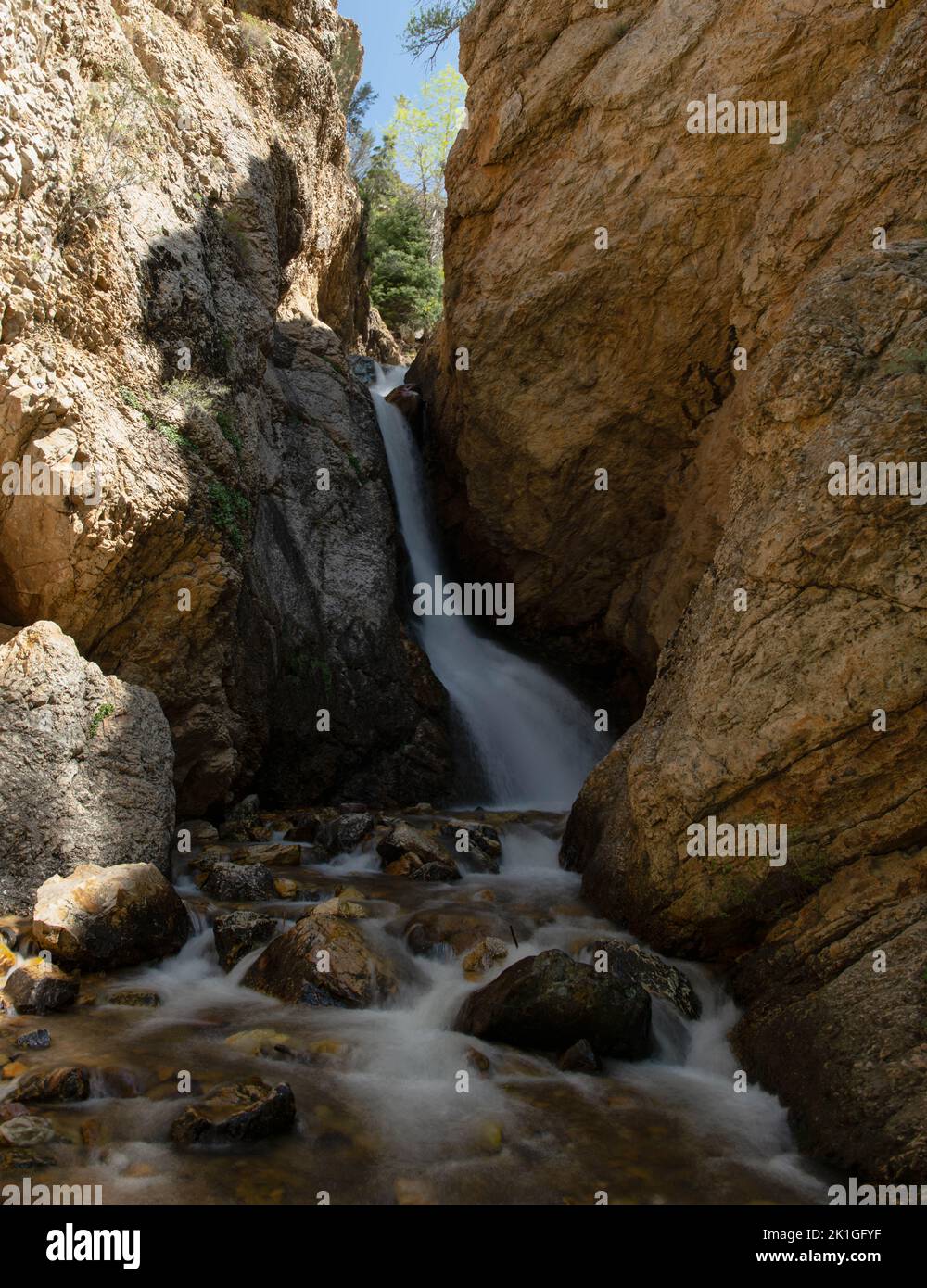 A vertical shot of a small waterfall streaming from the middle of a ...