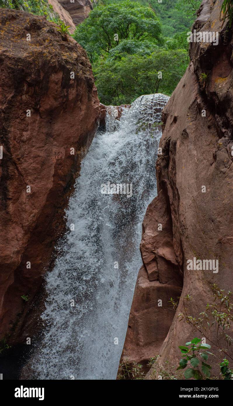A vertical shot of a small waterfall streaming from the middle of a ...