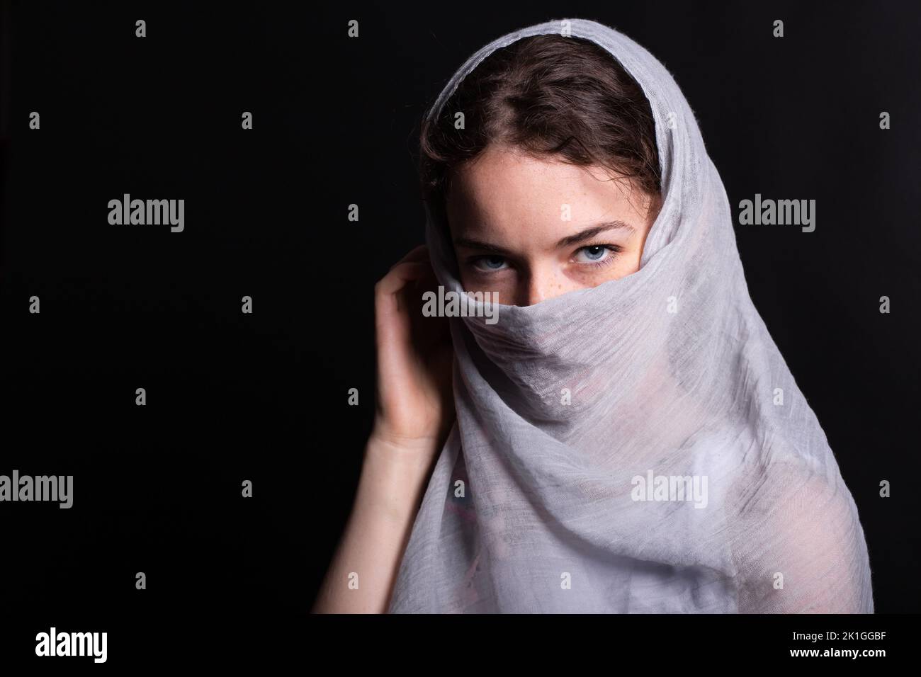 Beautiful young woman in a headscarf on a black background is modest ...