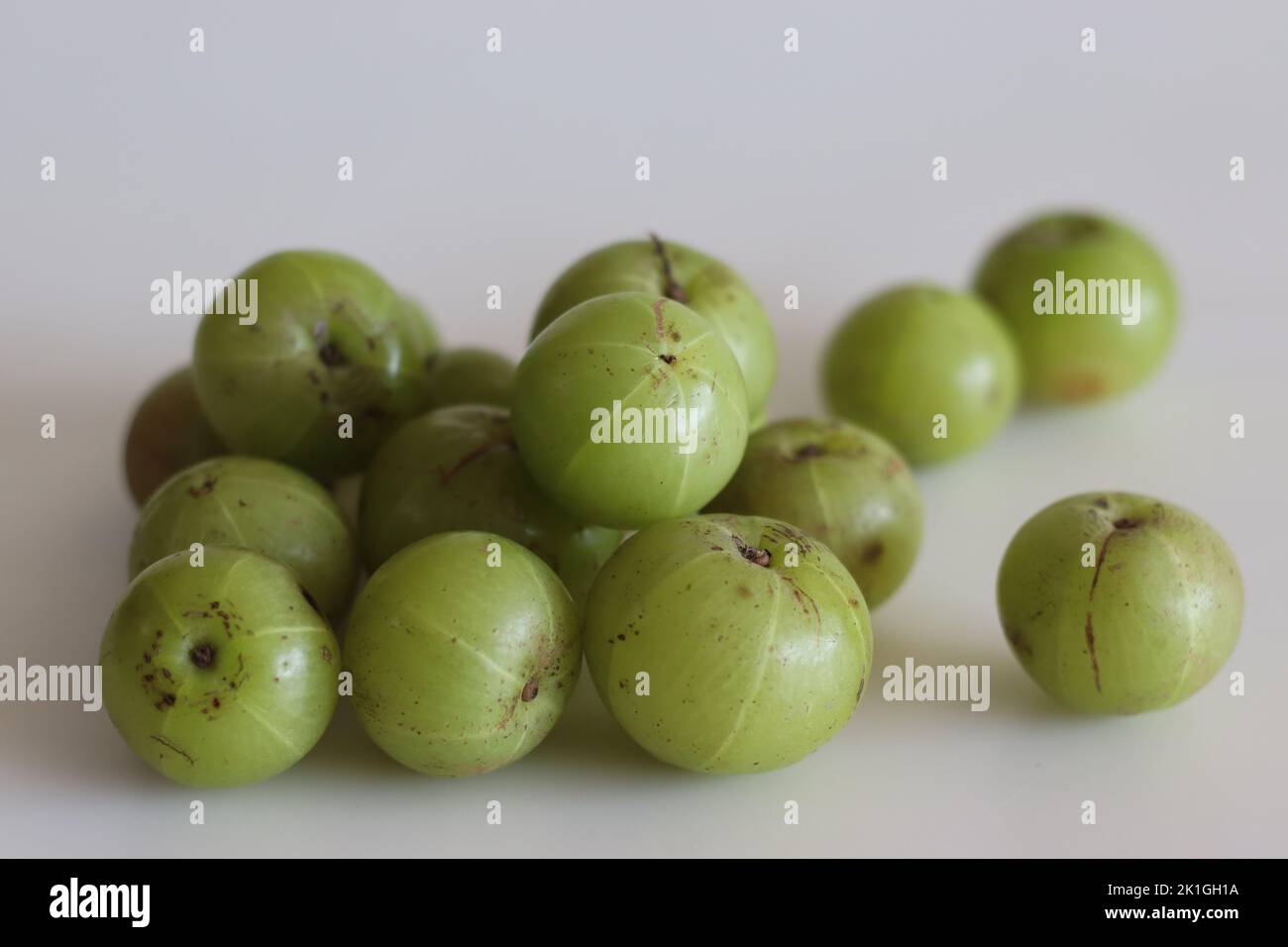 Amla or gooseberries shot on a white background. A translucent green ...