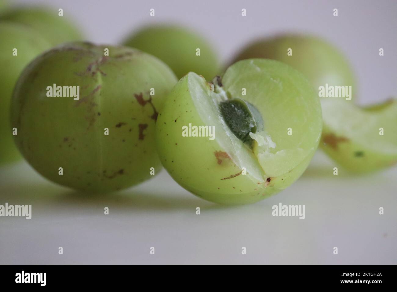 Amla or gooseberries shot on a white background. A translucent green ...