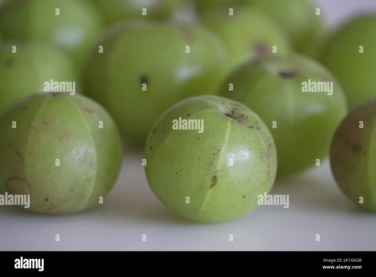 Amla or gooseberries shot on a white background. A translucent green ...