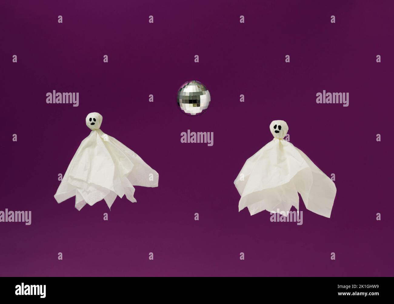 White paper ghosts on a Halloween party with disco ball and purple ...