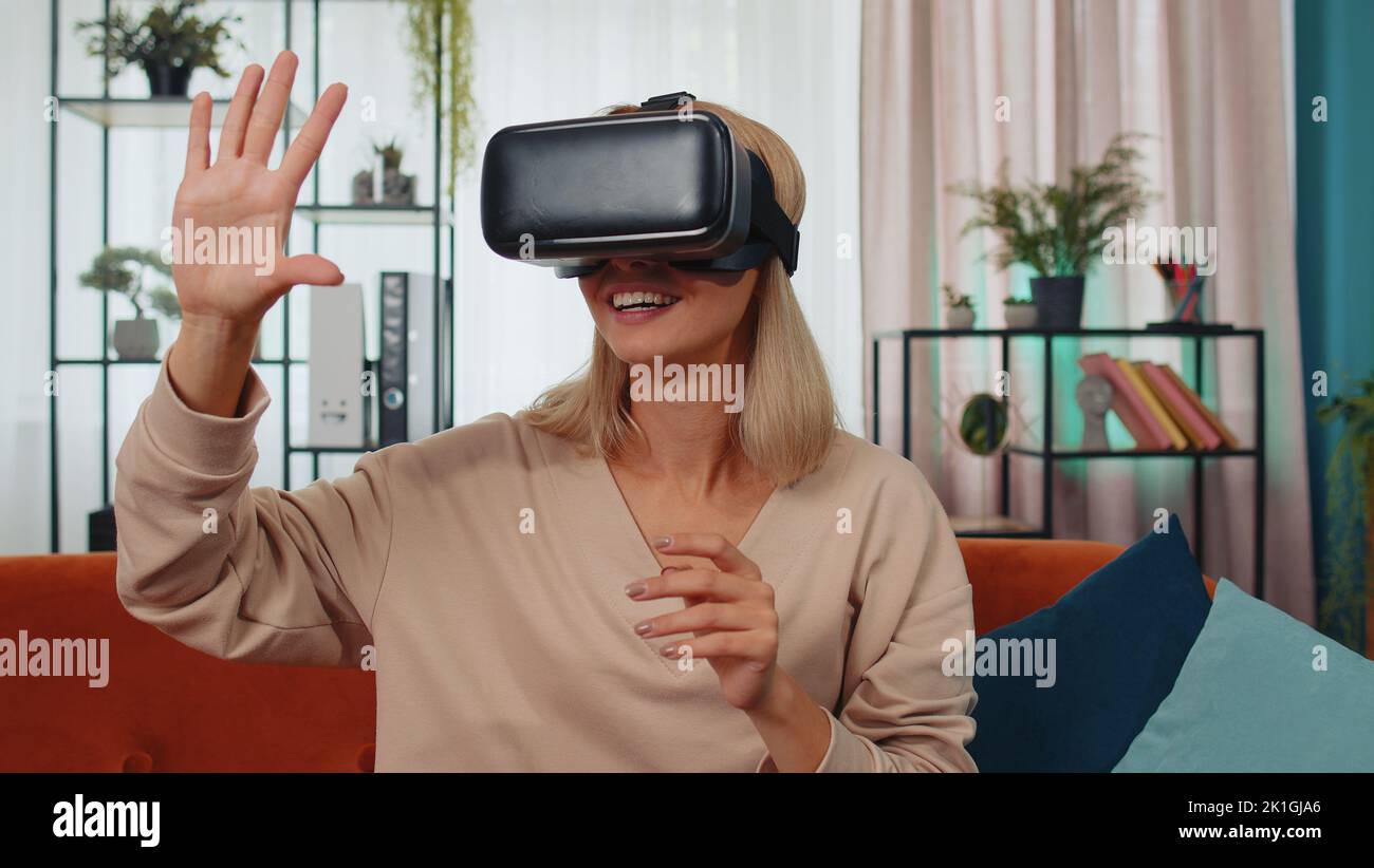 Young Caucasian girl wearing VR headset resting at home sitting on sofa ...