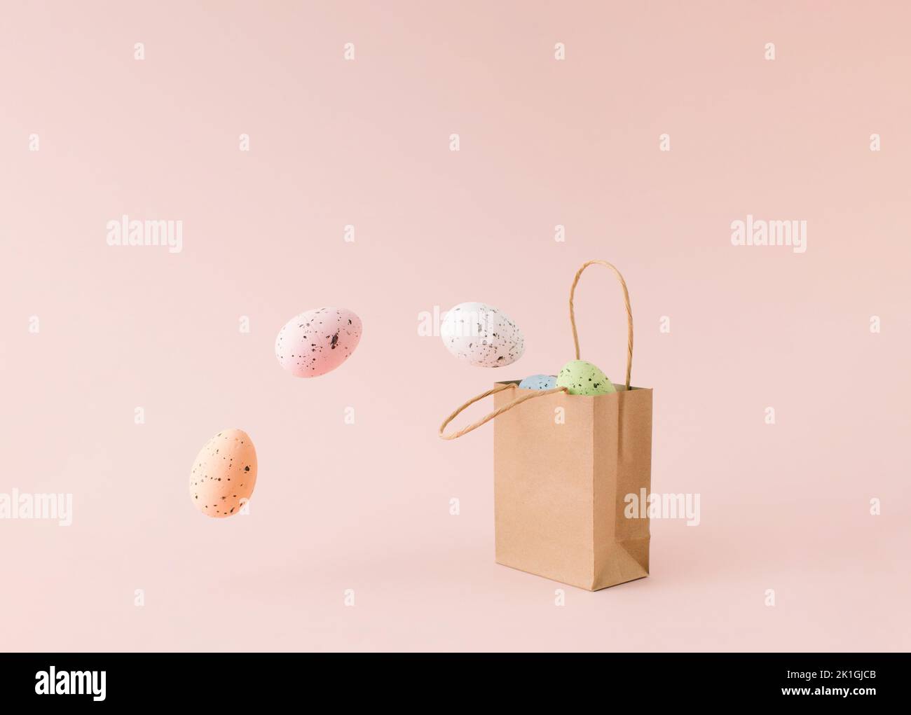Easter eggs jumping into brown paper shopping bag on pink surface Stock ...