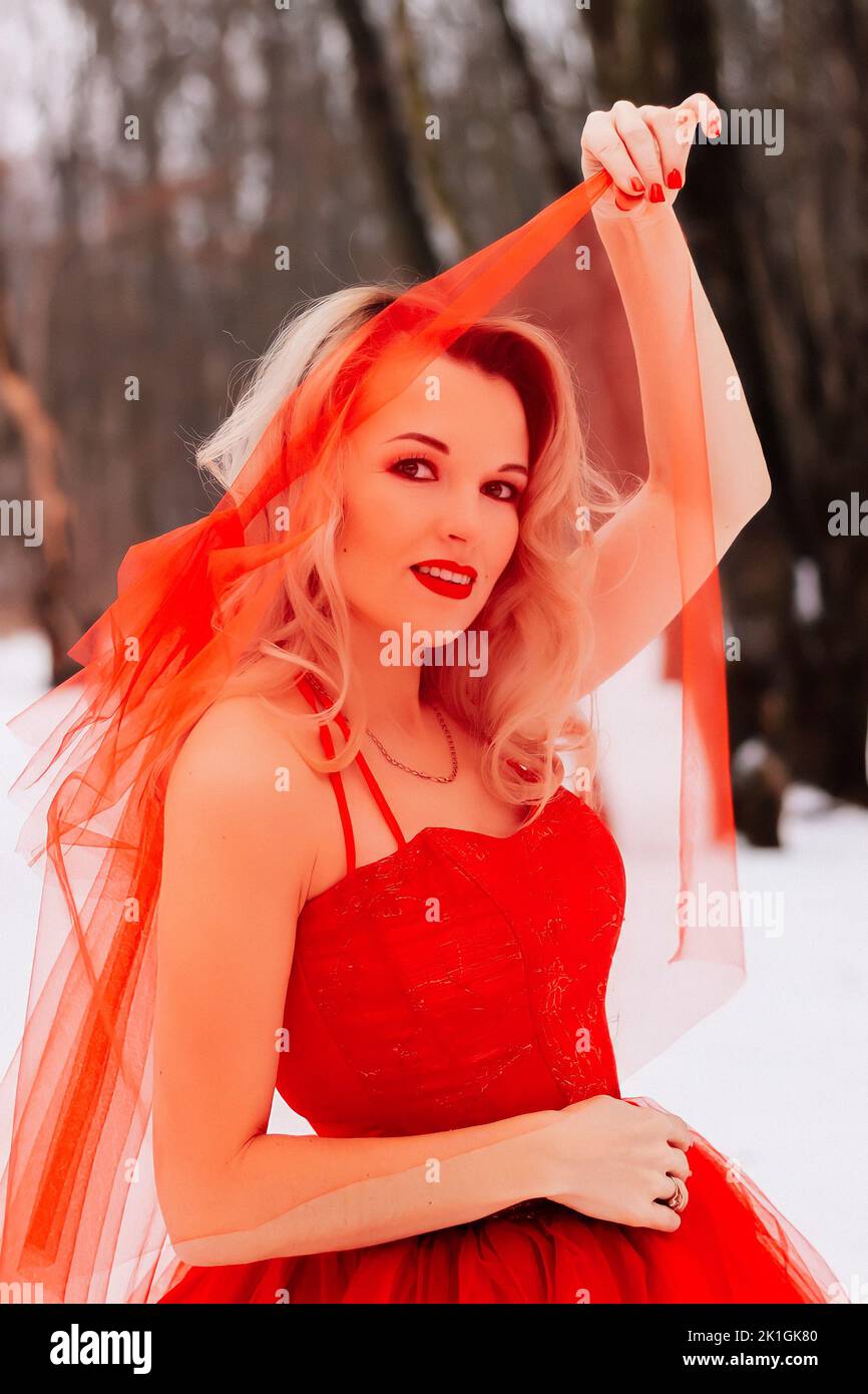 Beautiful woman in a luxurious red fairy-tale dress in a snowy forest ...