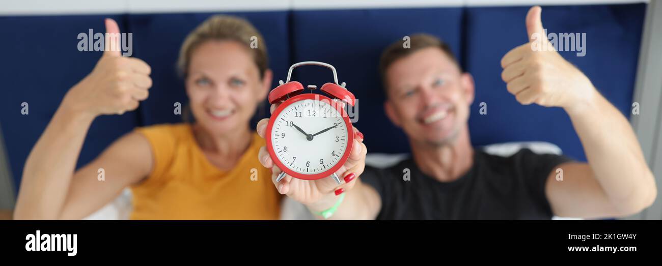 Married couple is holding alarm clock and thumbs up gesture Stock Photo ...
