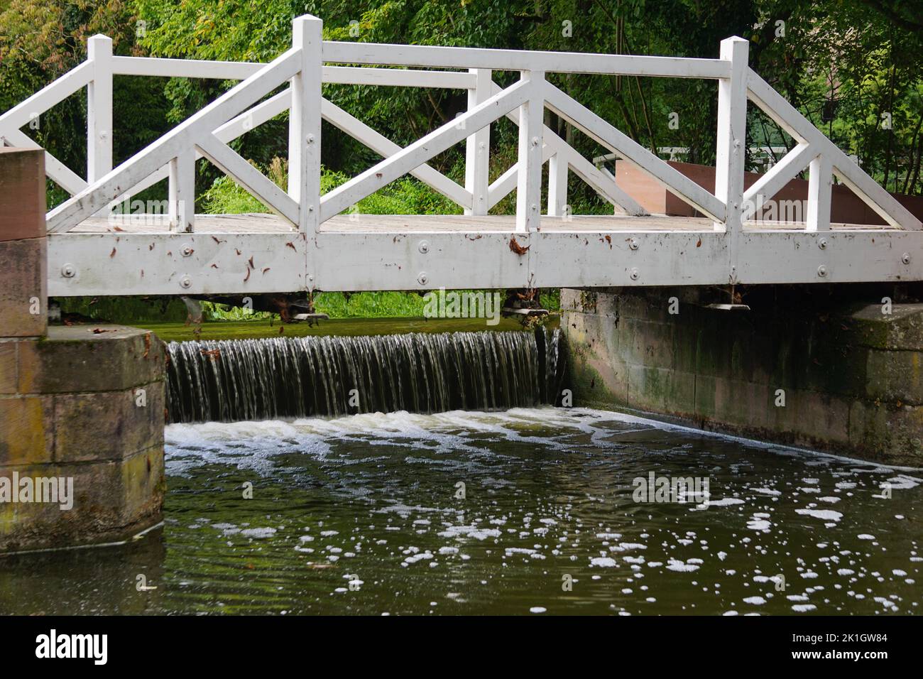 A beautiful view of a small white bridge over the stream in a park in ...