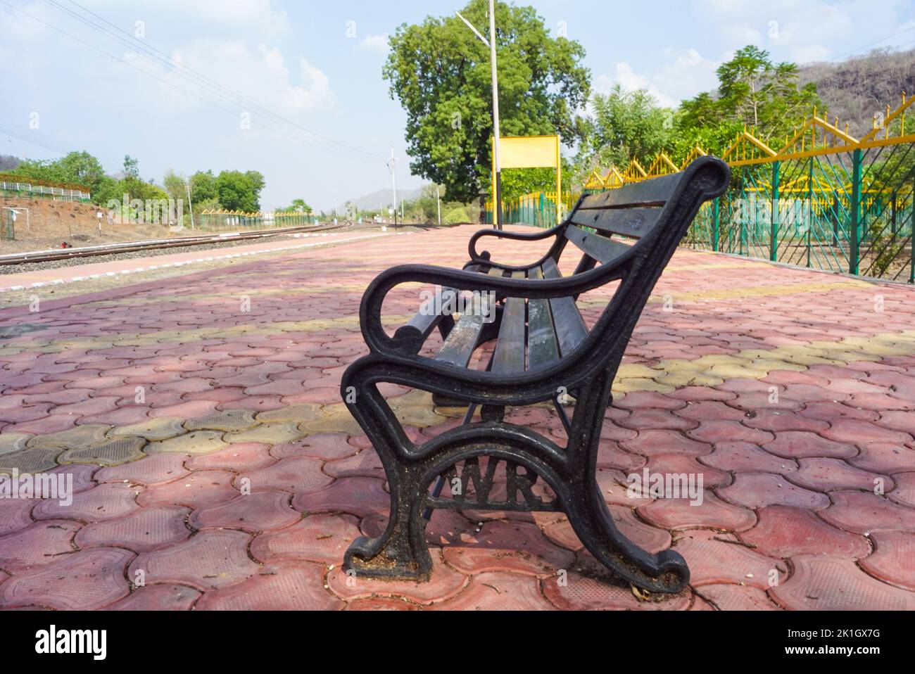 Blank railway sign board, seating bench at railway station platform of ...