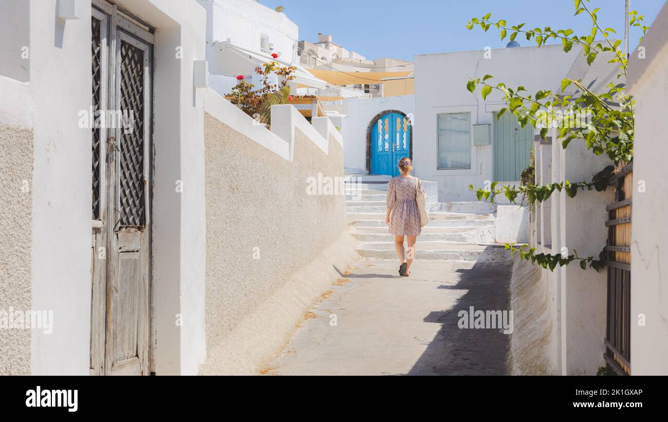 A young blonde female tourist explores and wanders throough the ...