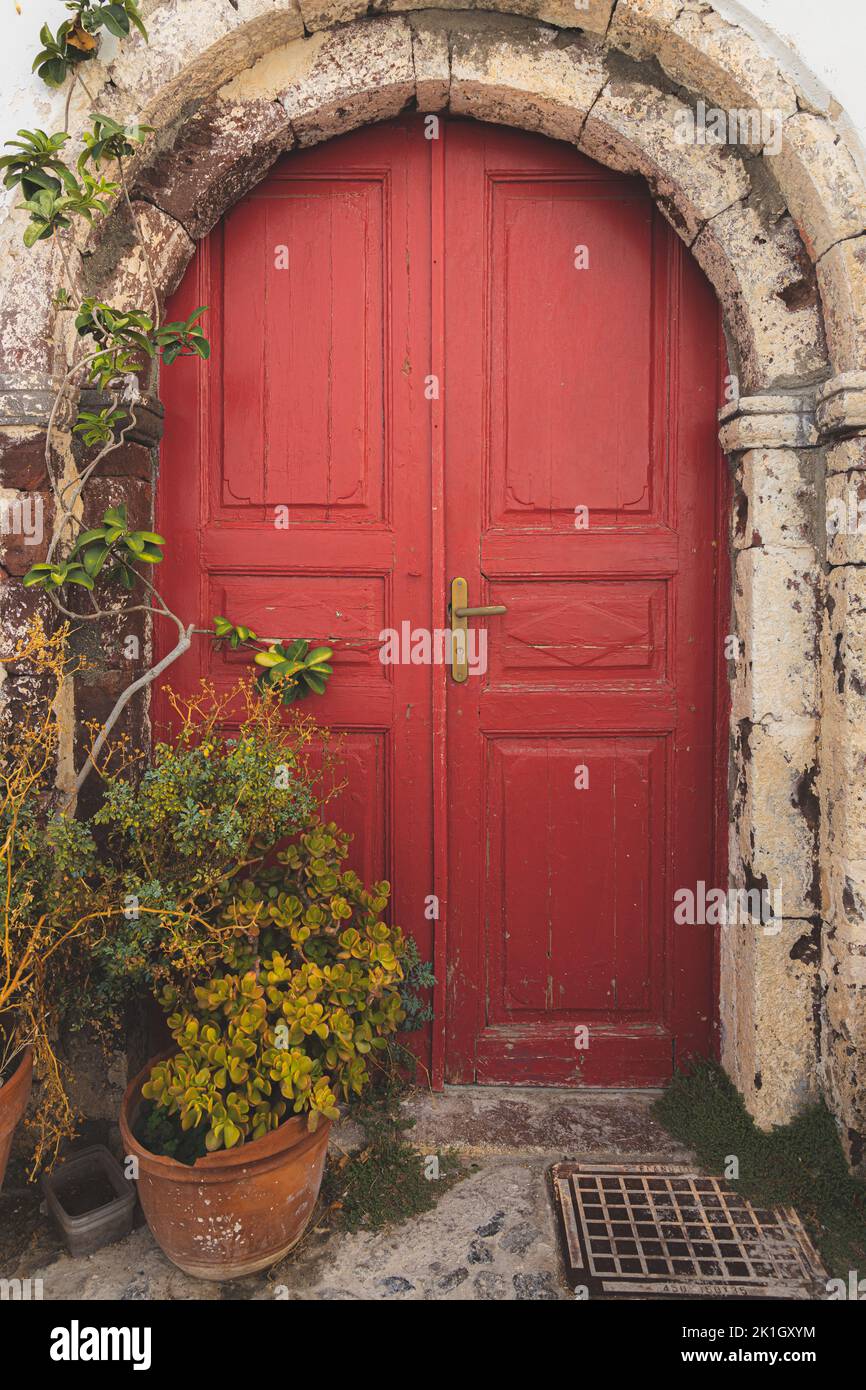 Detail of a traditional and decorative, red door under a stone archway ...