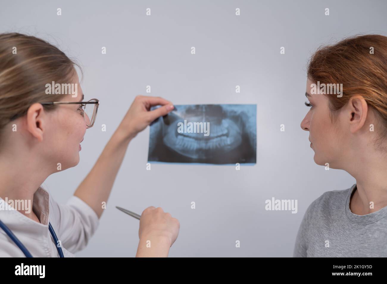 A woman doctor and a patient at the reception are discussing an x-ray ...