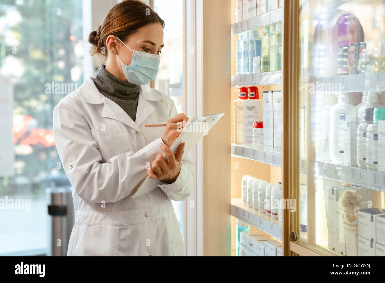White apothecary wearing lab coat and face mask working in pharmacy ...