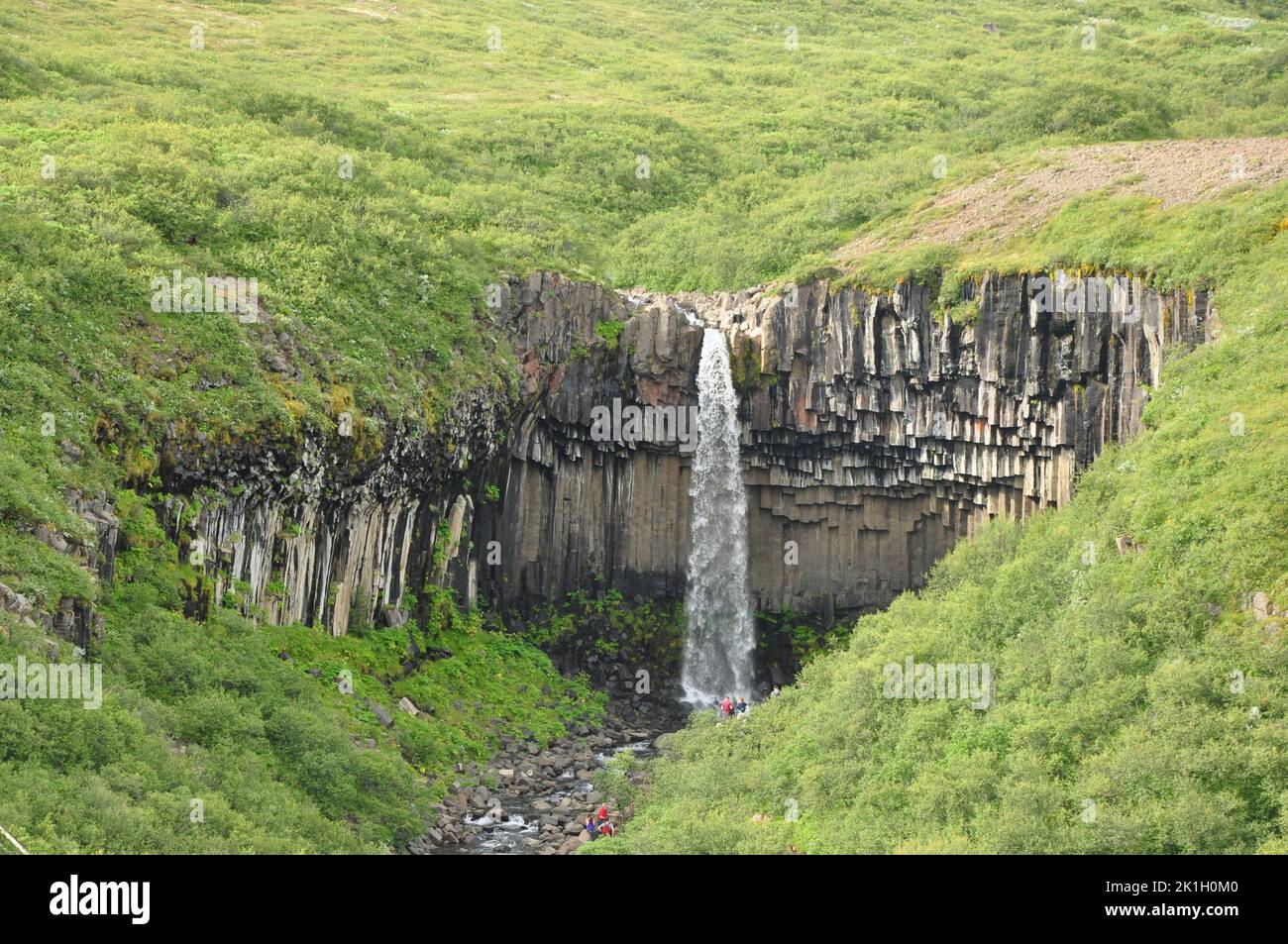 A Scenic view of a waterfall flowing between grass cliffs Stock Photo ...