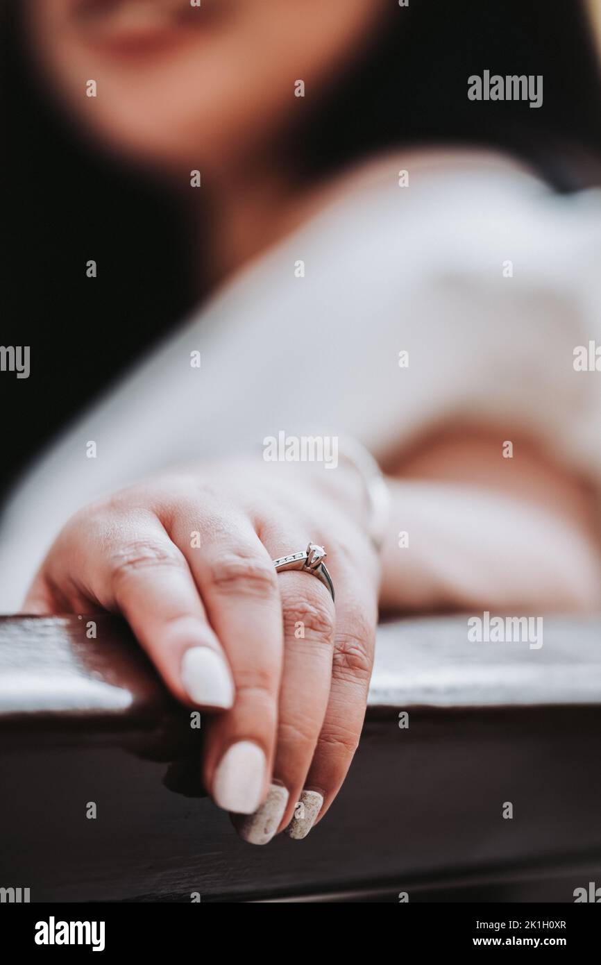 a girl sitting on a bench with a wedding ring or engagement ring ...