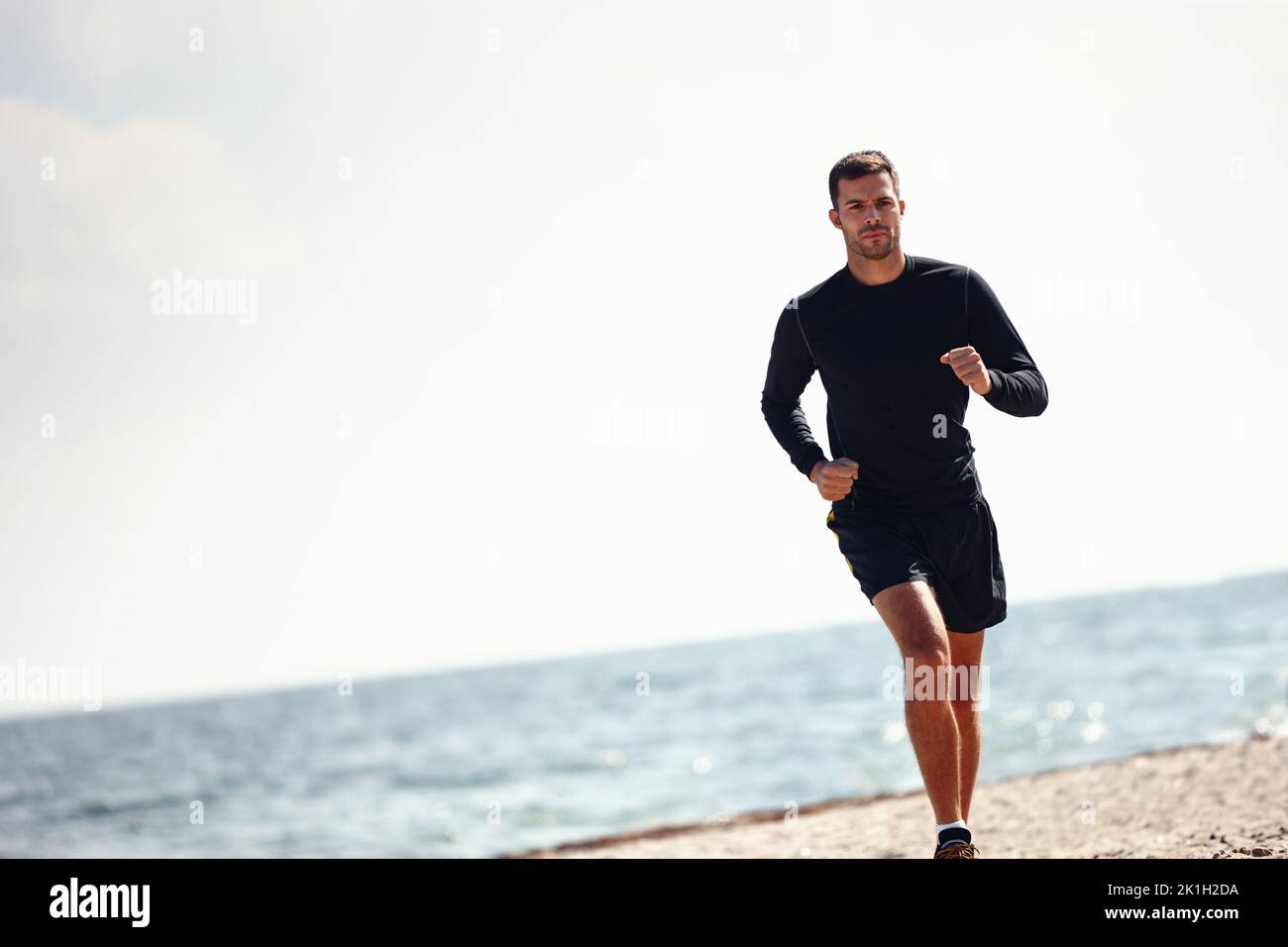 Training for a big run. a handsome young man running on the beach Stock ...